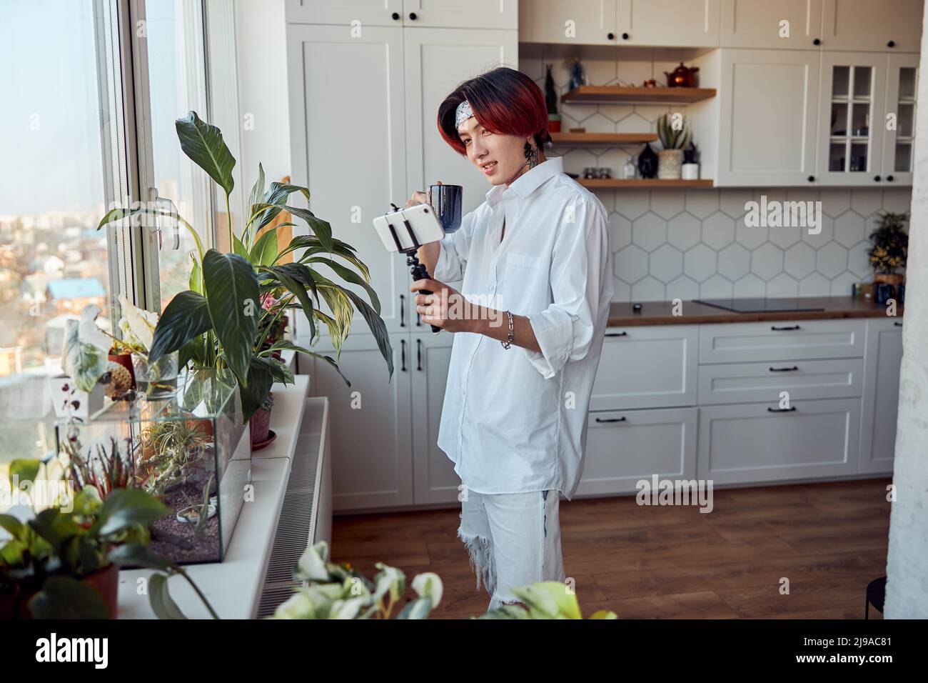 Asian guy holding the phone on a tripod and shooting video content ...