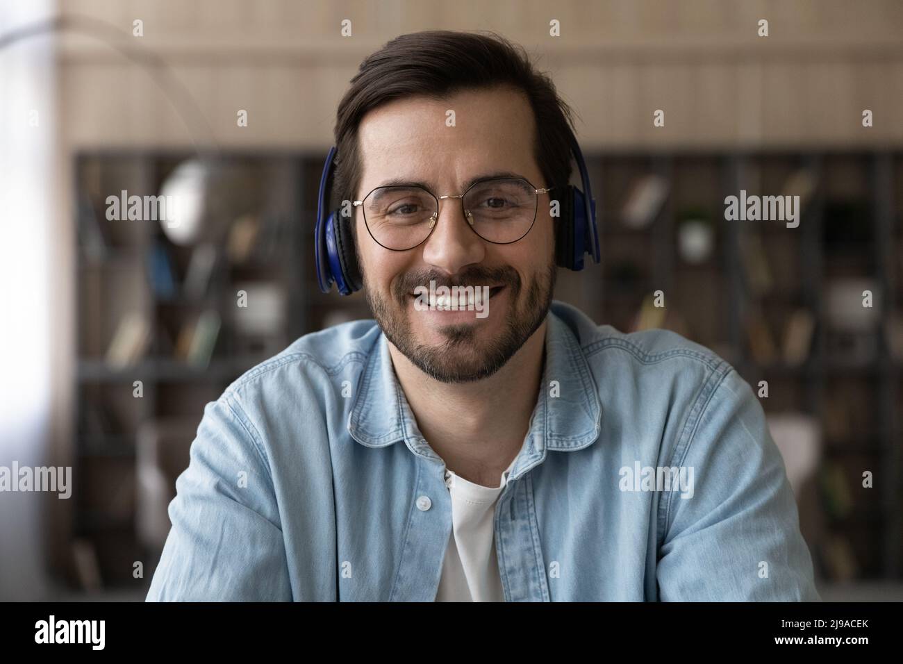 Smiling positive millennial male in headset looking at web camera Stock ...
