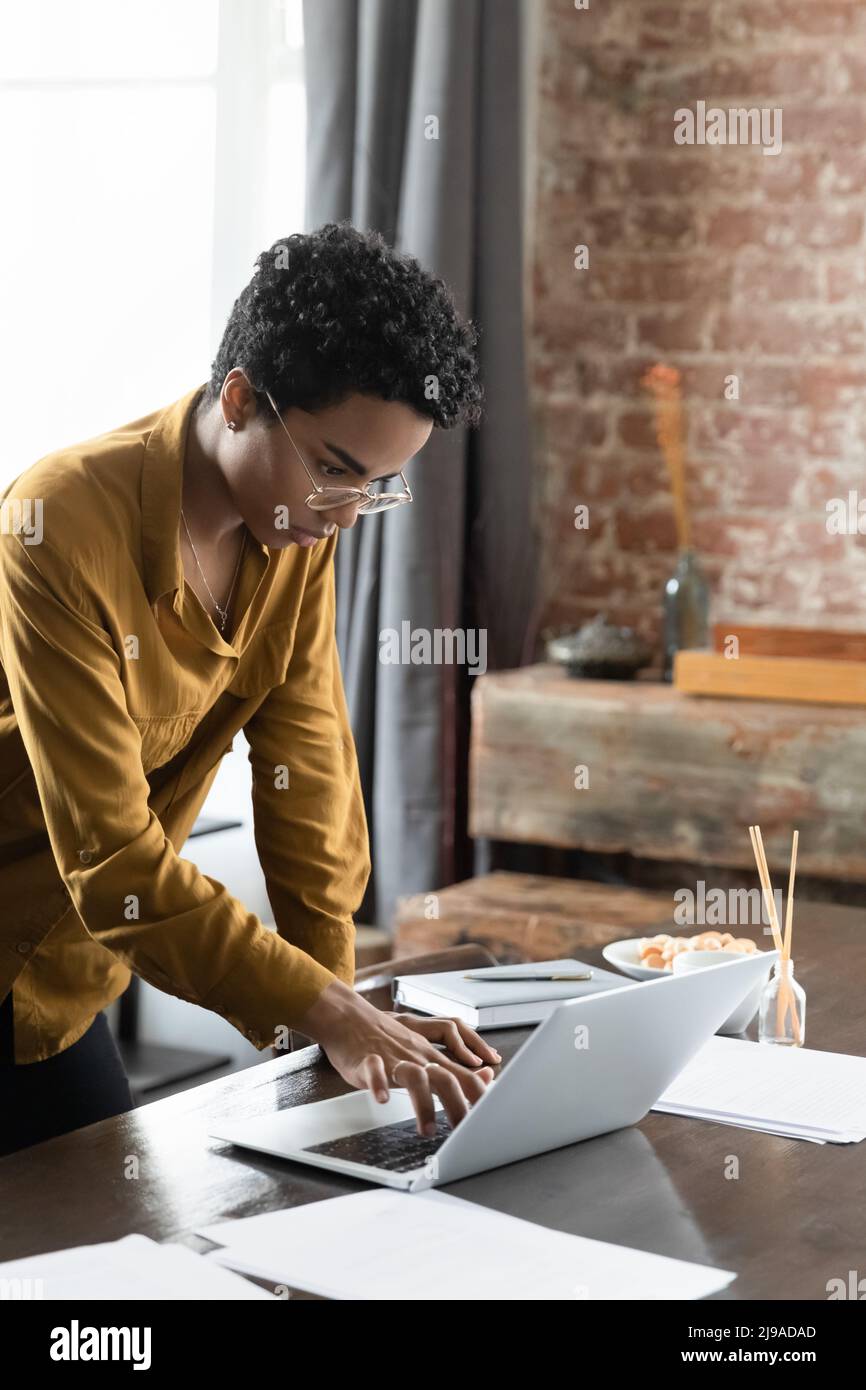 Thoughtful African woman lean over desk working on laptop Stock Photo ...