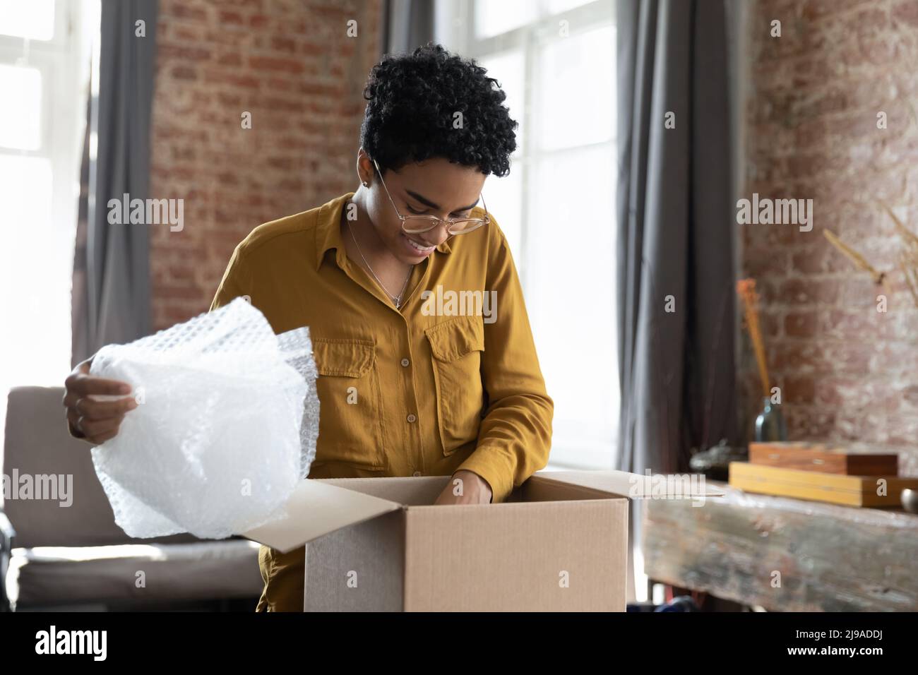 Smiling African woman unpack received parcel box Stock Photo - Alamy