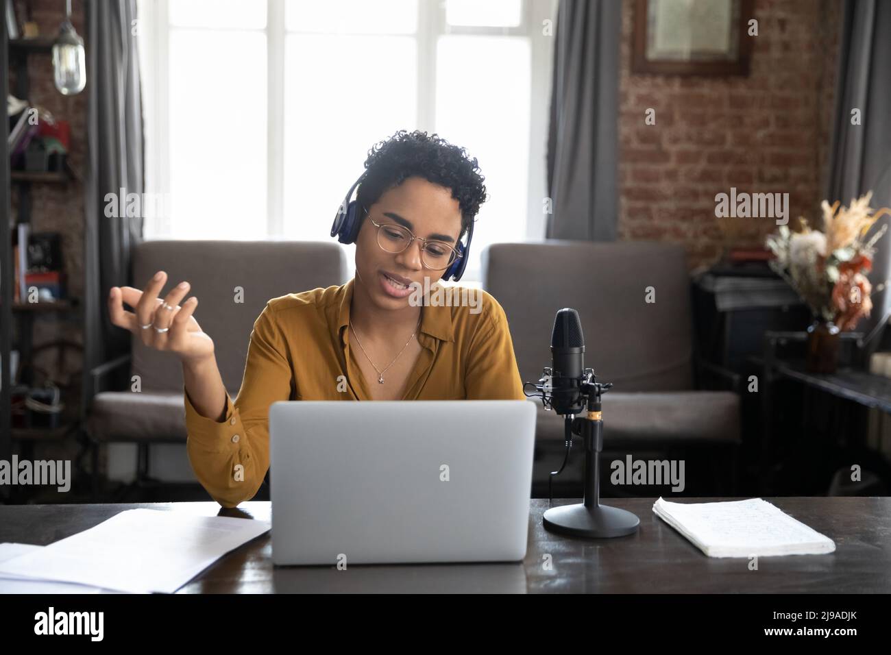 African woman wear headphones looks at laptop, talks into microphone ... African woman wear headphones looks at laptop, talks into microphone ...