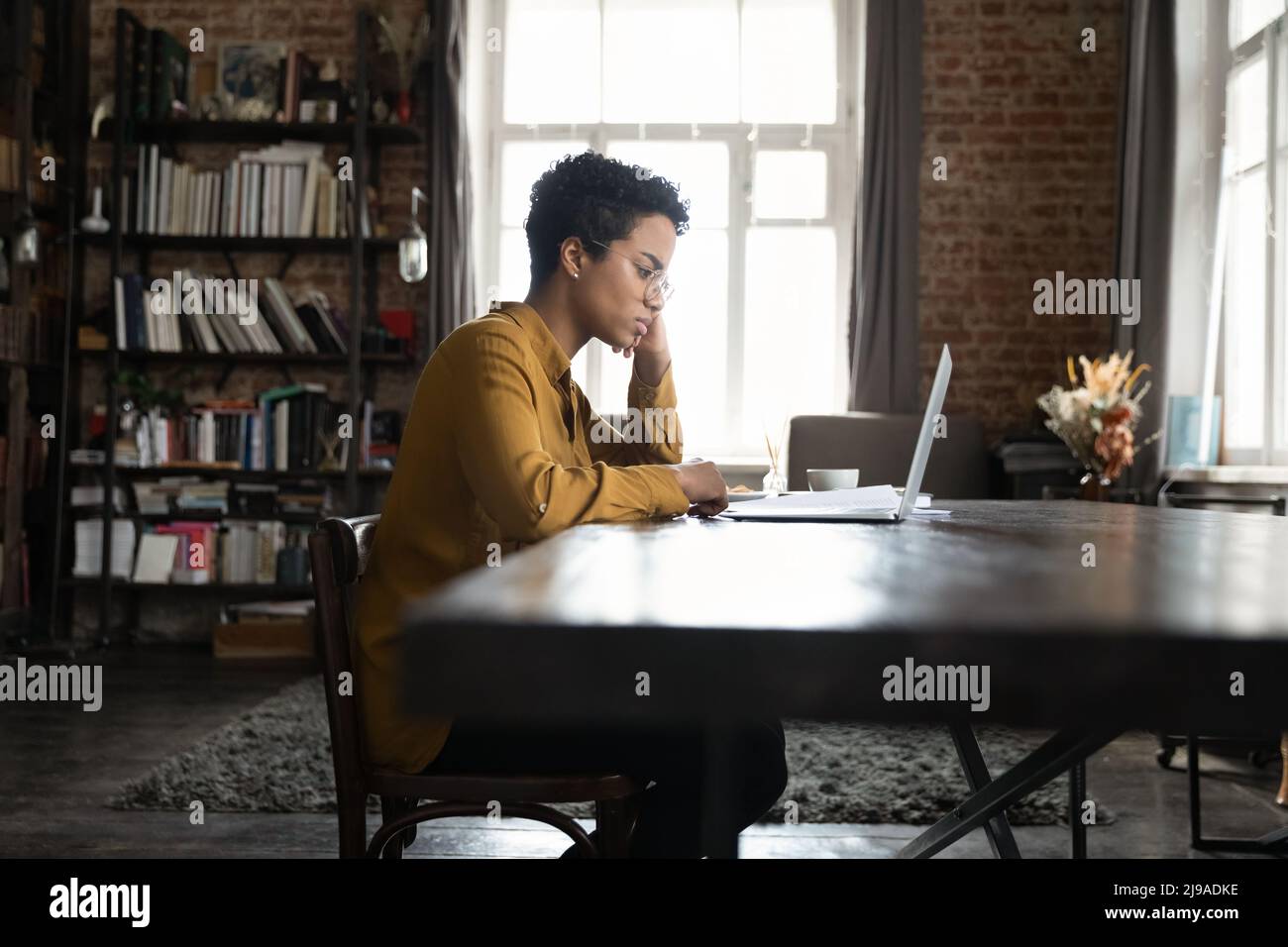 Serious African woman staring at laptop screen, side view Stock Photo ...