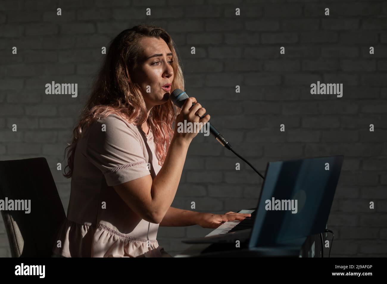 Expressive female singer has a video blog on a laptop. Portrait of a ...