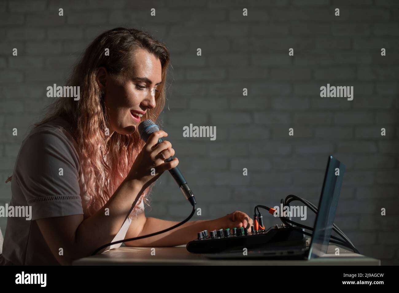 A woman sings into a microphone and plays online. A female blogger is ...