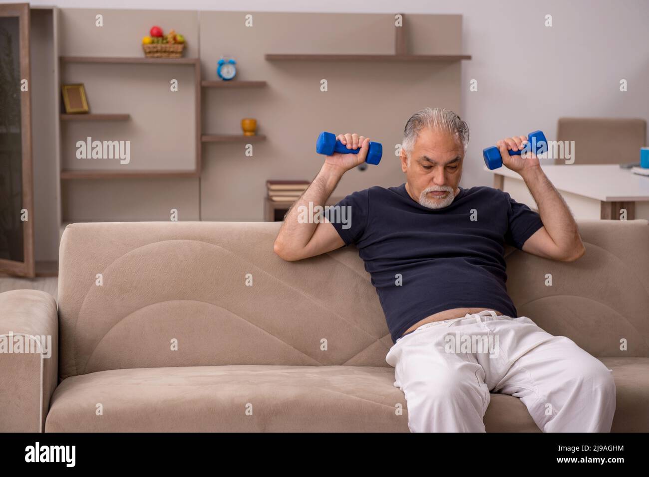 Old man doing sport exercises indoors Stock Photo - Alamy