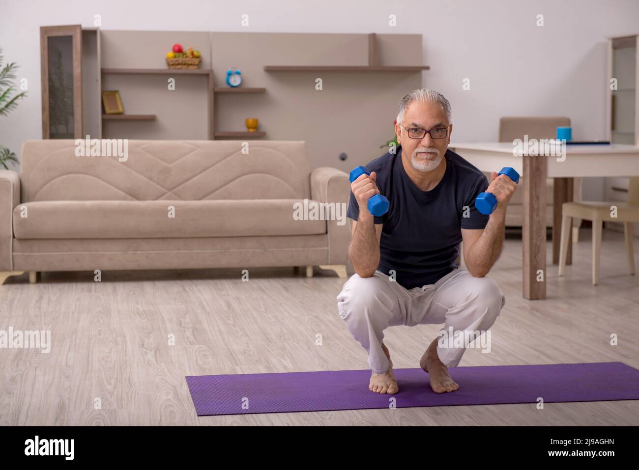 Old man doing sport exercises indoors Stock Photo - Alamy