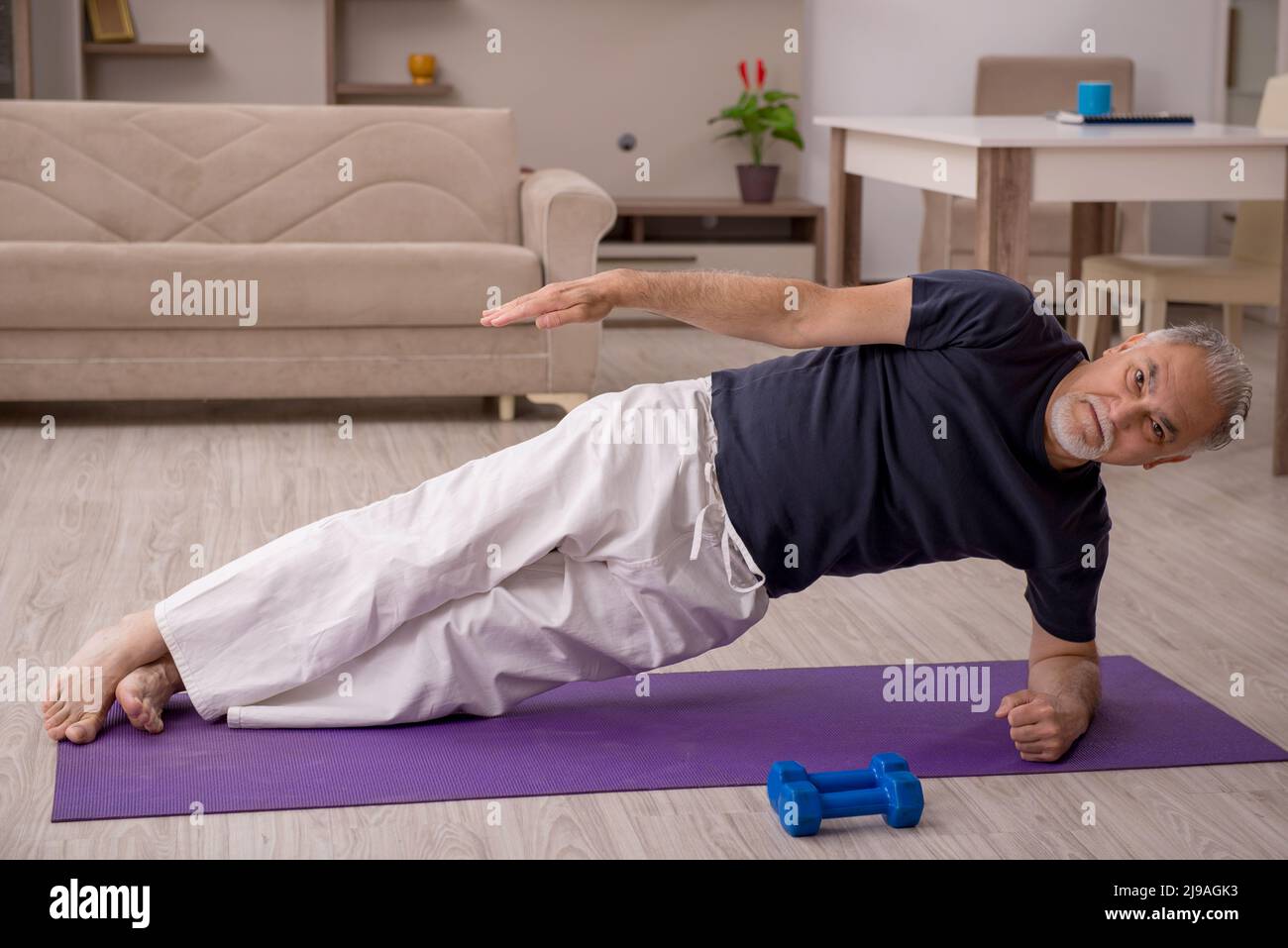 Old man doing sport exercises indoors Stock Photo - Alamy