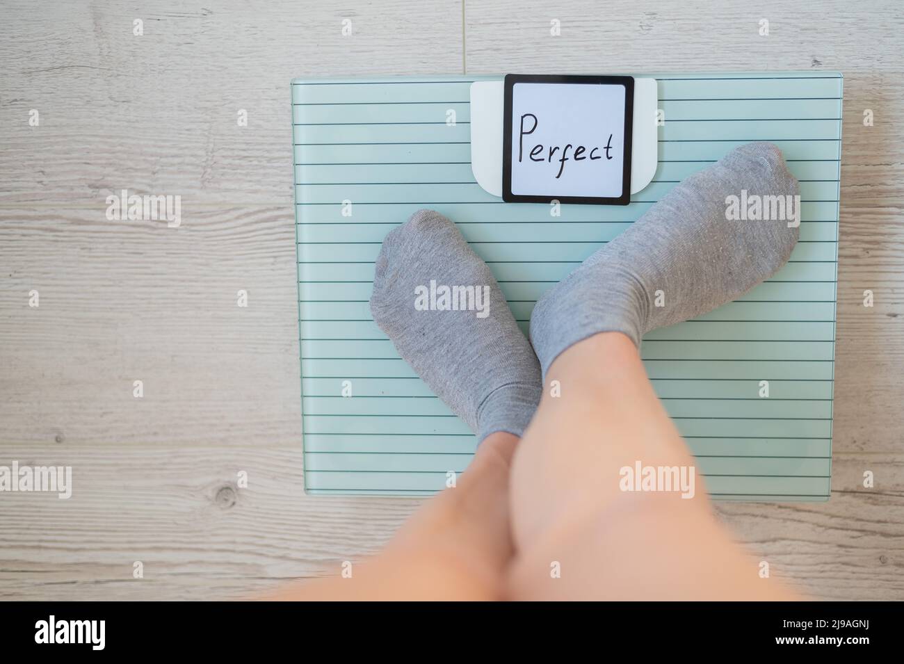 Faceless woman measures weight on the floor scales. Top view of women's ...