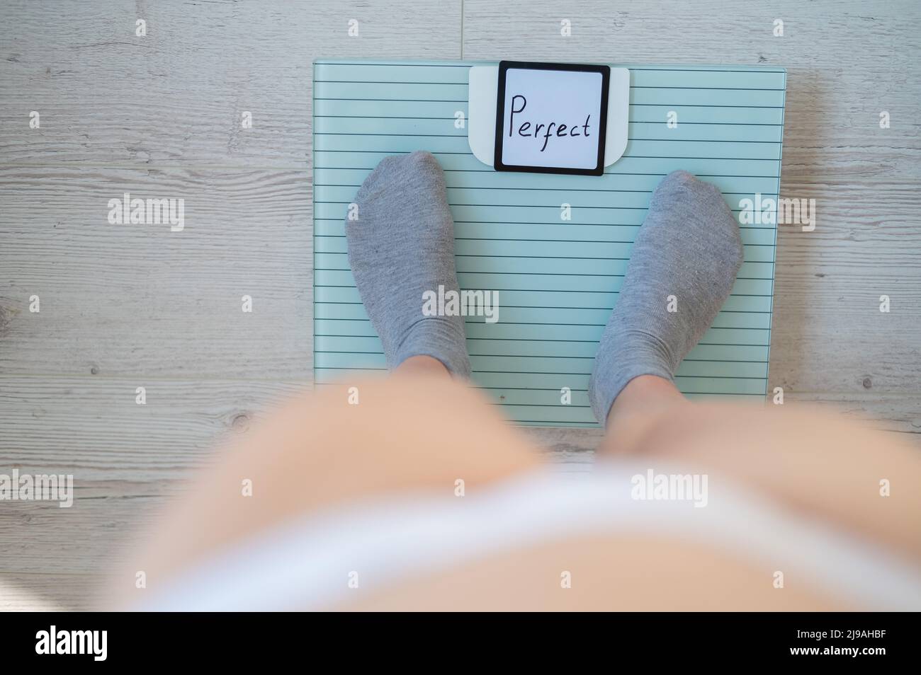 Faceless woman measures weight on the floor scales. Top view of women's ...