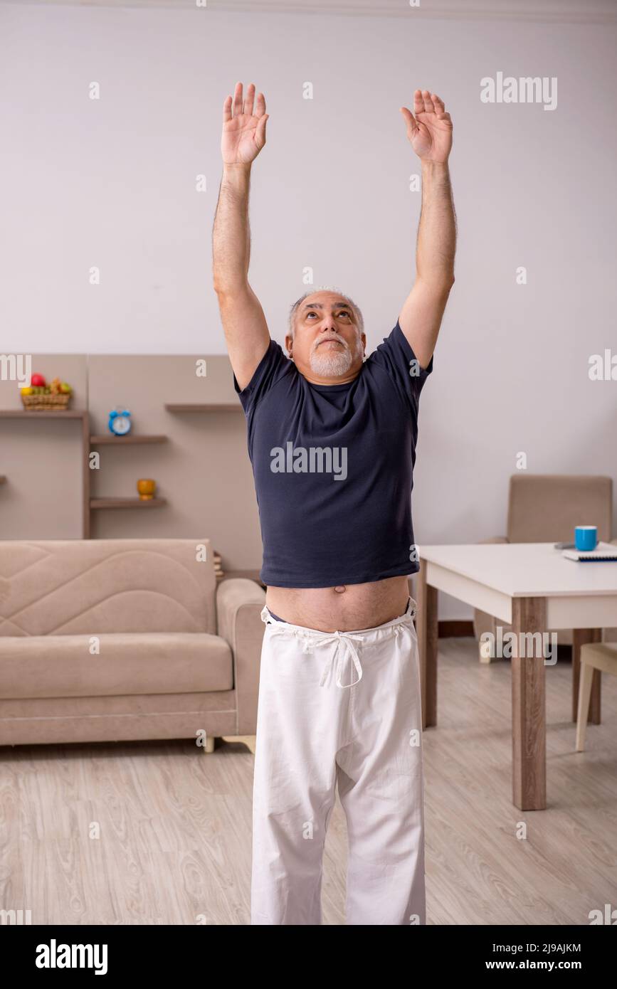 Old man doing sport exercises indoors Stock Photo - Alamy