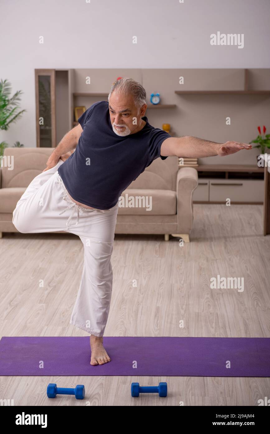 Old man doing sport exercises indoors Stock Photo - Alamy