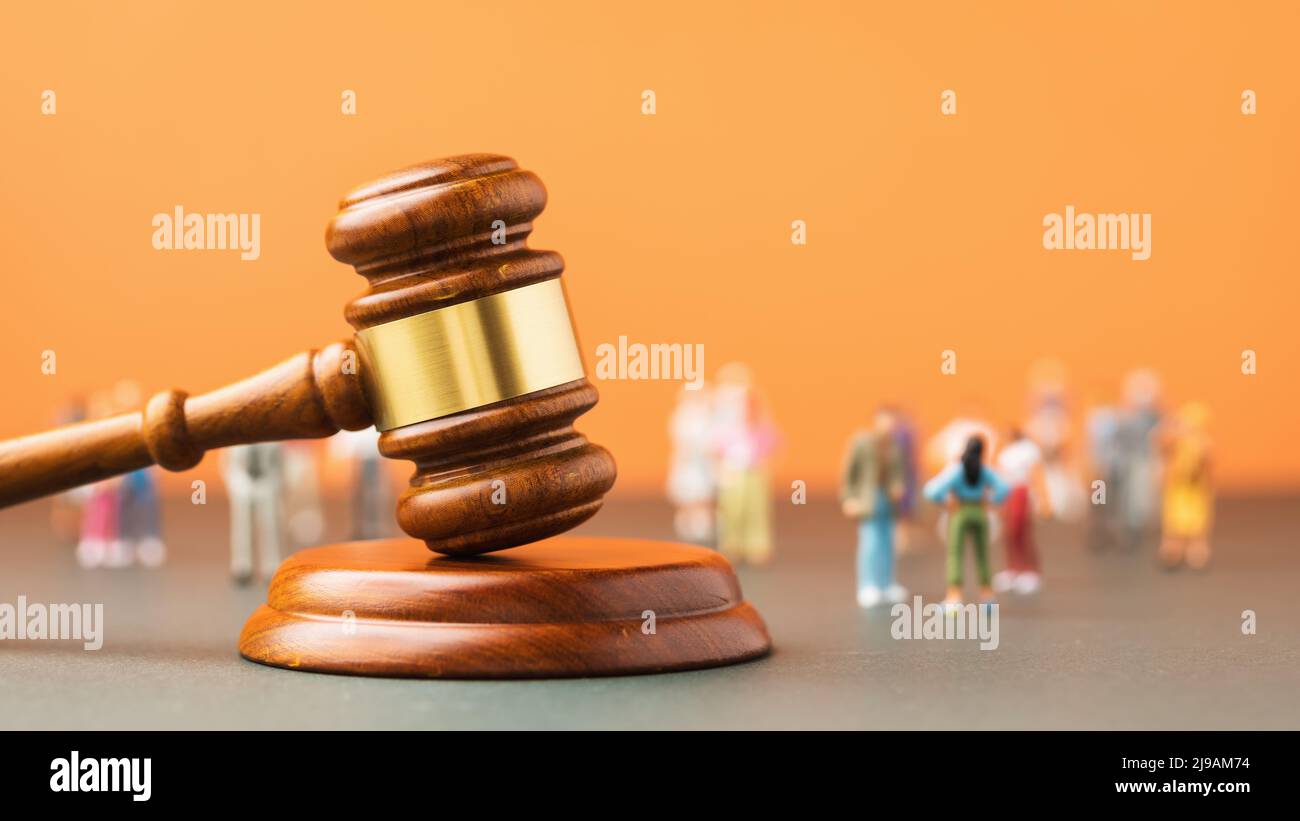 Judicial gavel and plastic toy men on a colored background, a concept ...