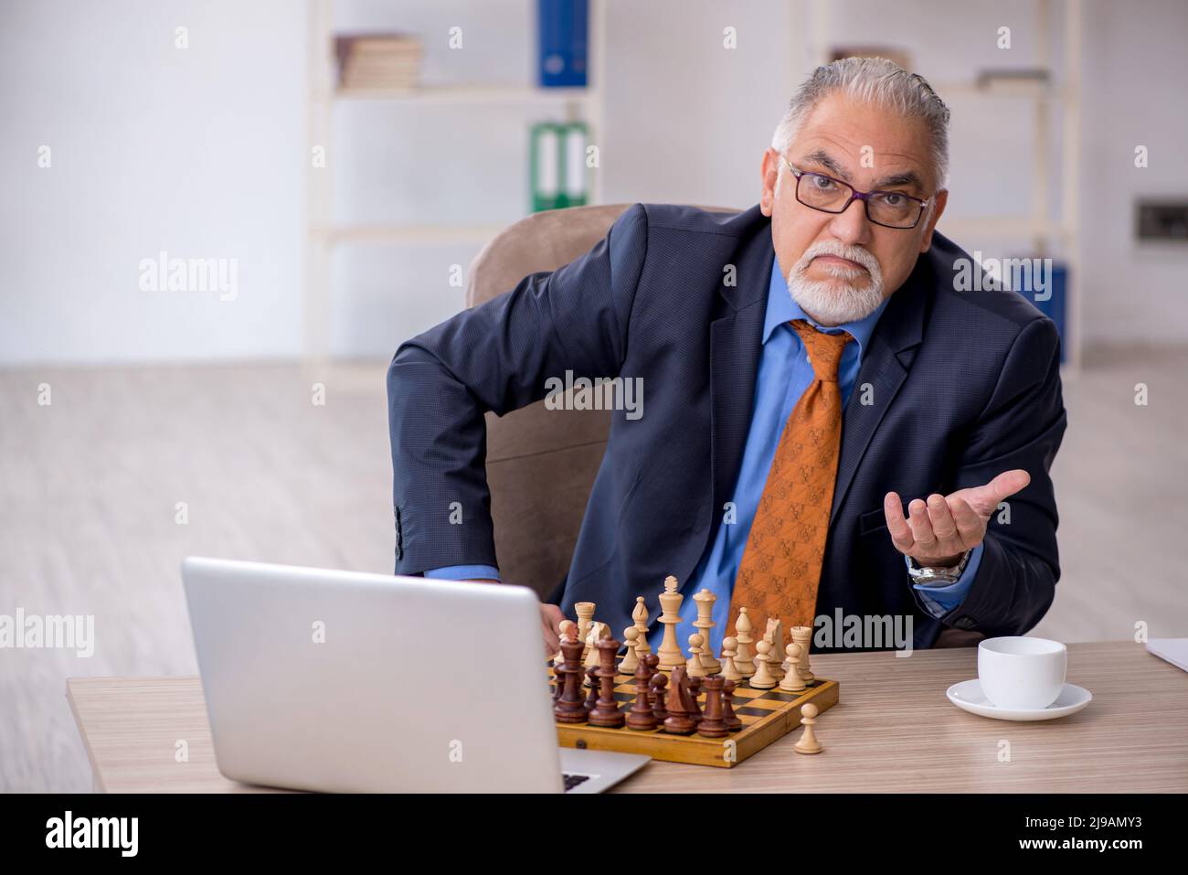 Old businessman playing chess in the office Stock Photo - Alamy