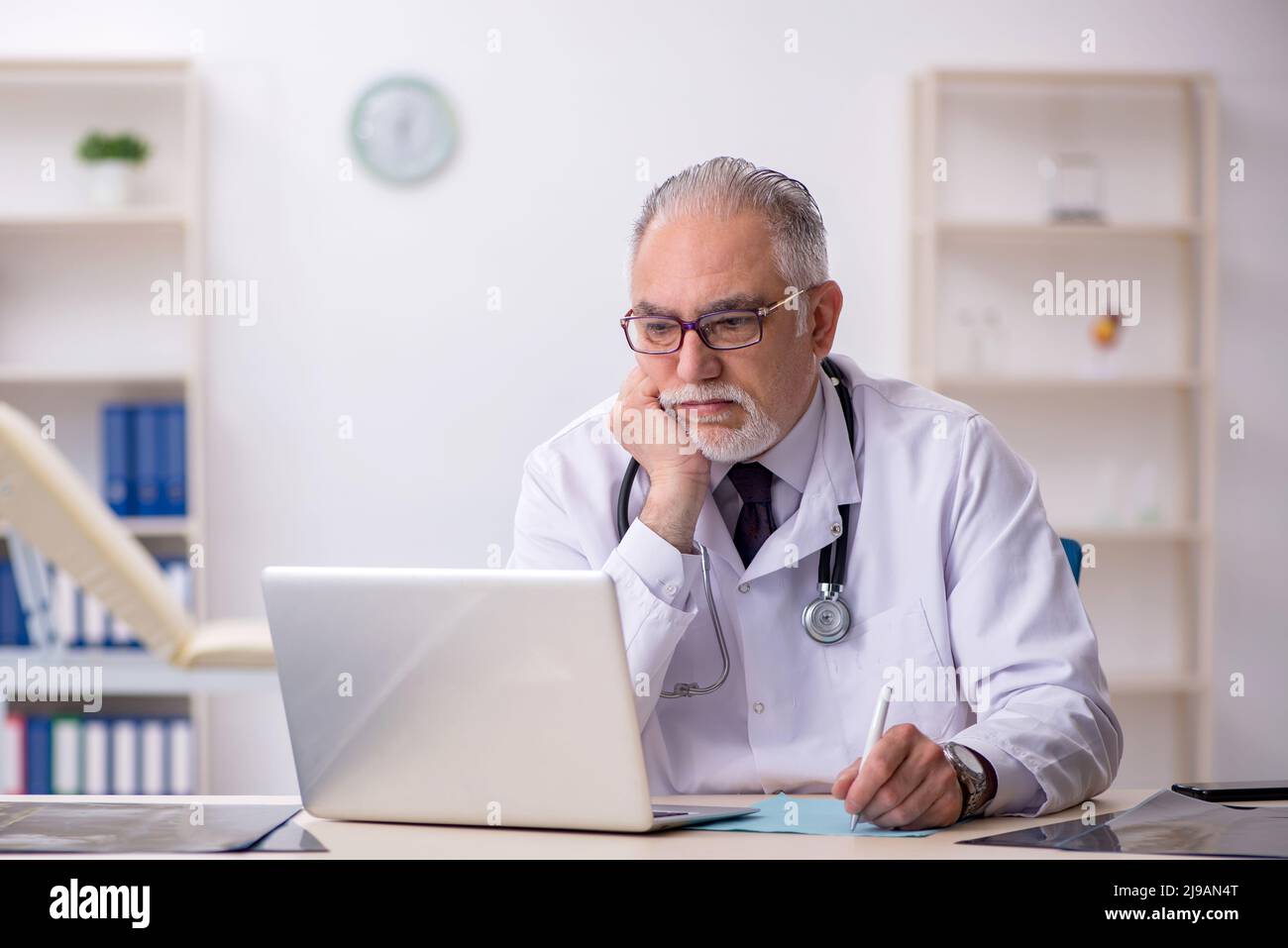 Old male doctor working in the clinic Stock Photo - Alamy