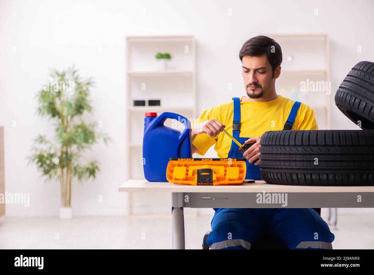 Young garage worker with tyre at workshop Stock Photo - Alamy
