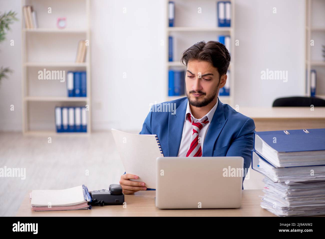 Young businessman employee and too much work at workplace Stock Photo ...