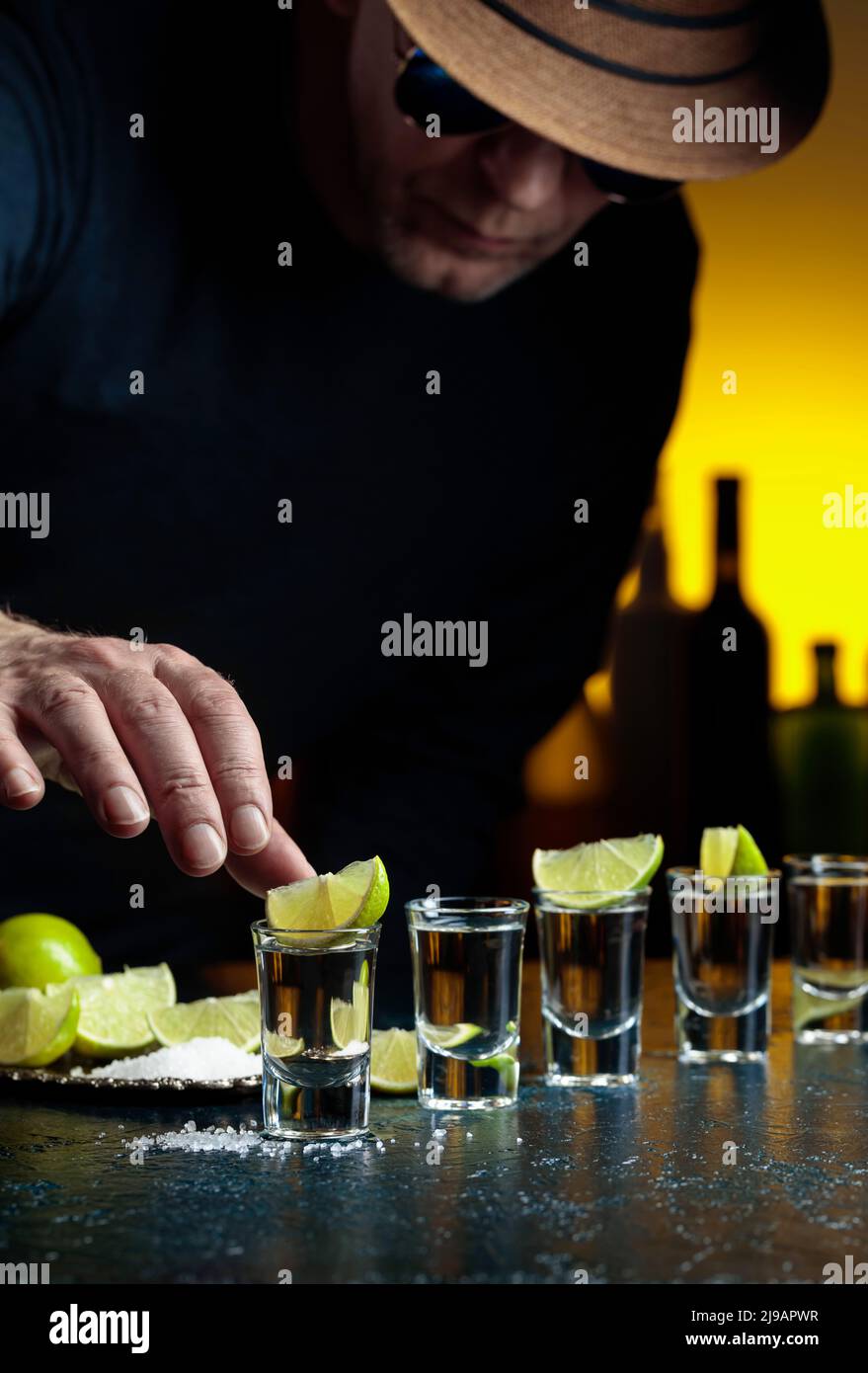 Man in the hat is drinking tequila with salt and lime slices. Selective ...
