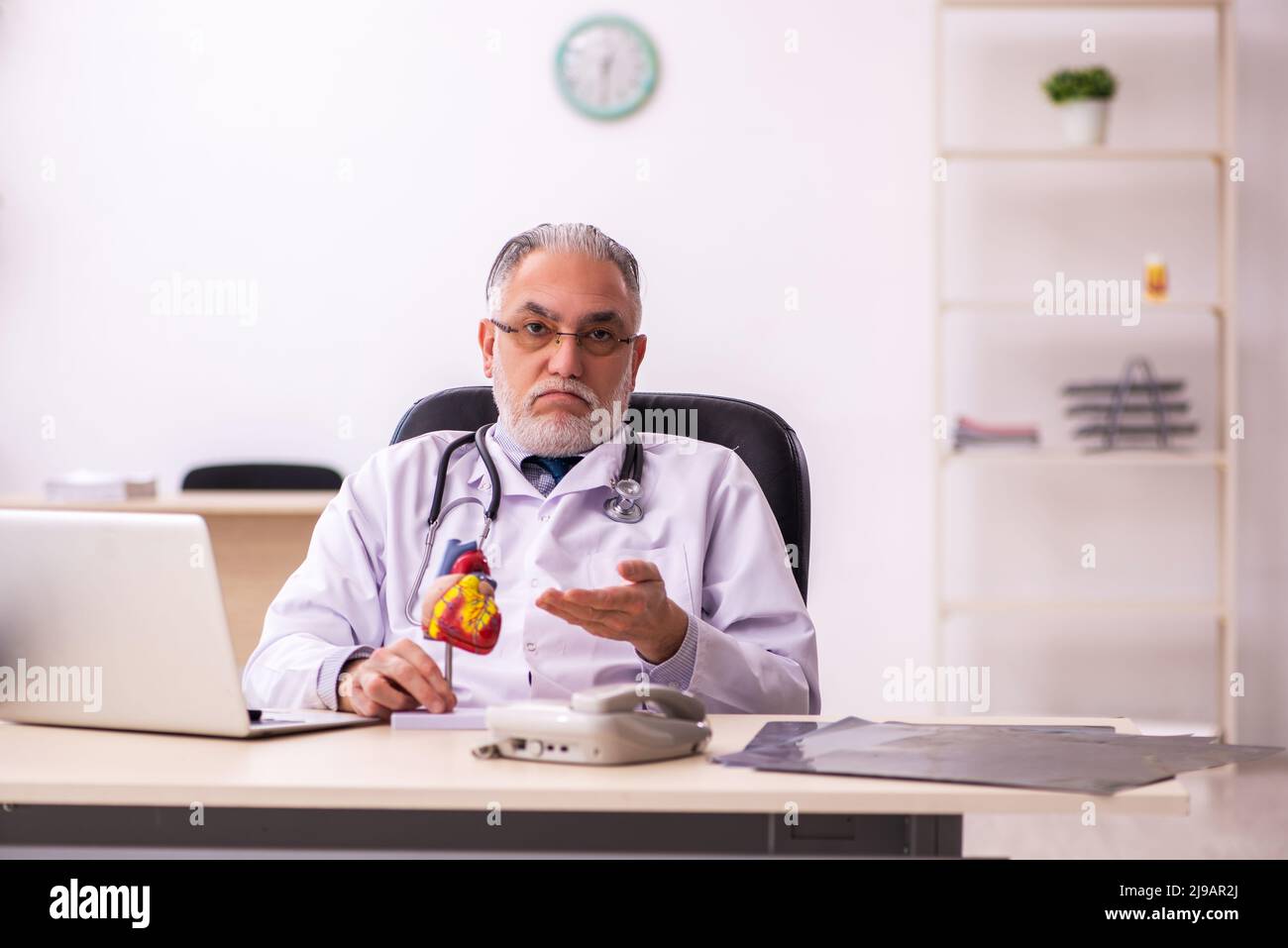 Aged male doctor cardiologist working at workplace Stock Photo - Alamy