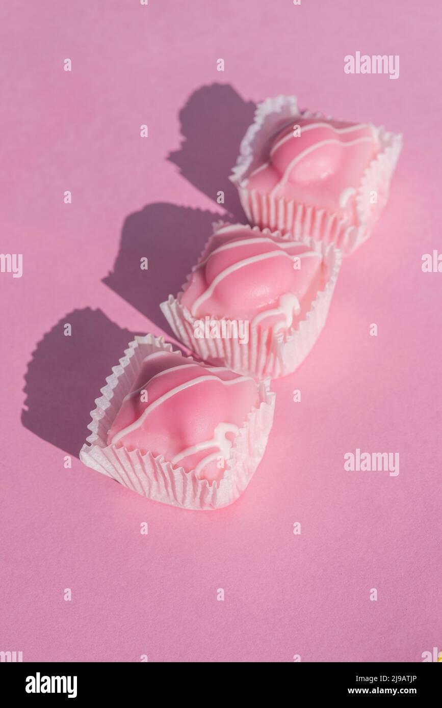 Pink fondant icing on sponge cakes set on a pastel pink background ...
