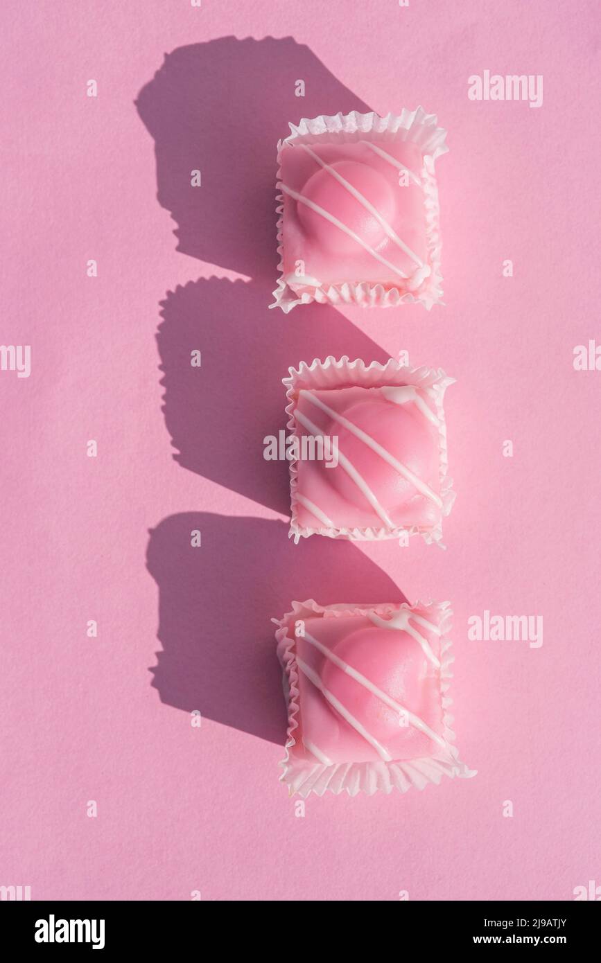 Pink fondant icing on sponge cakes set on a pastel pink background ...
