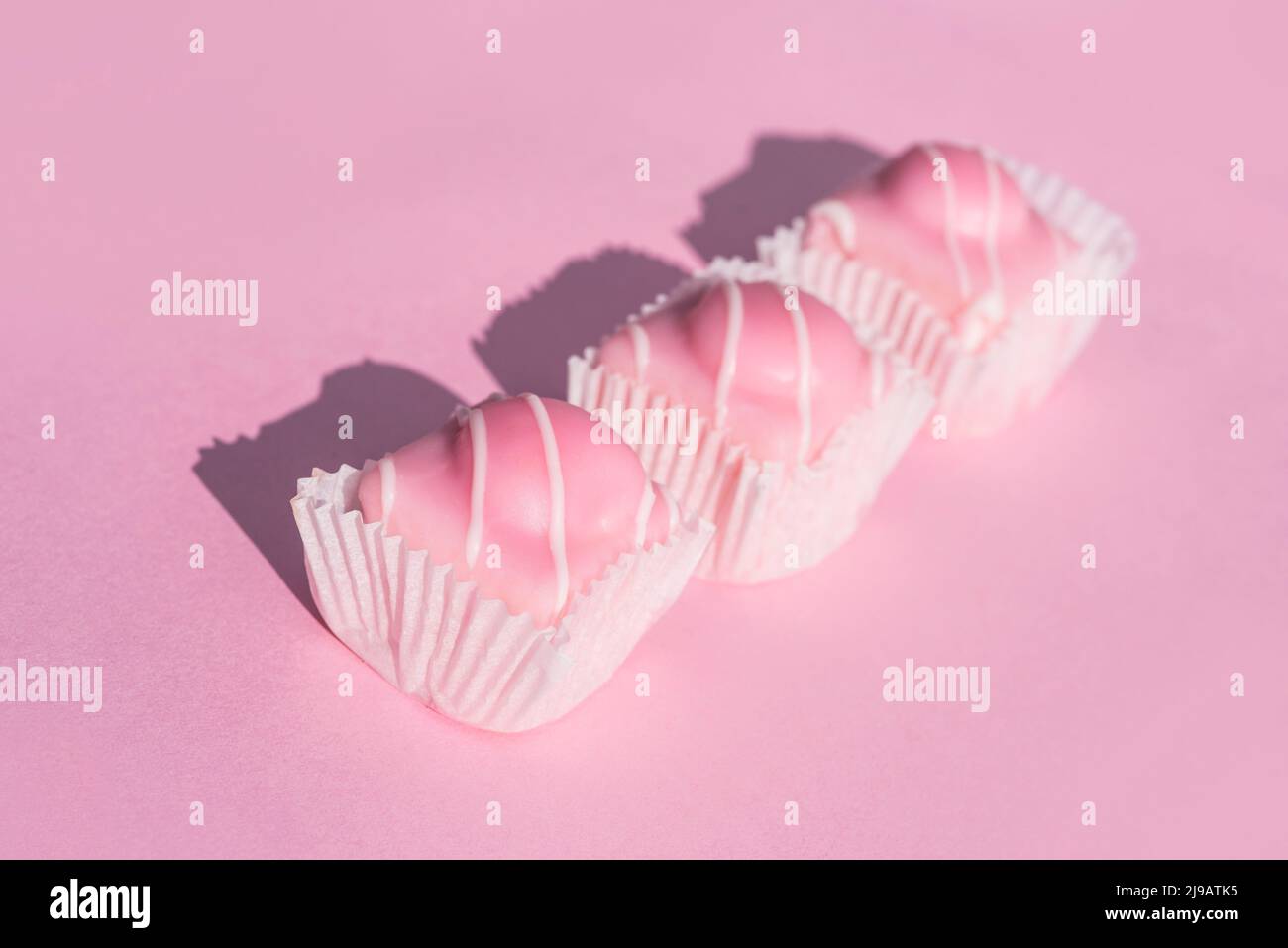 Pink fondant icing on sponge cakes set on a pastel pink background ...