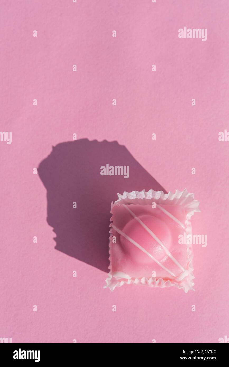 Pink fondant icing on sponge cakes set on a pastel pink background ...