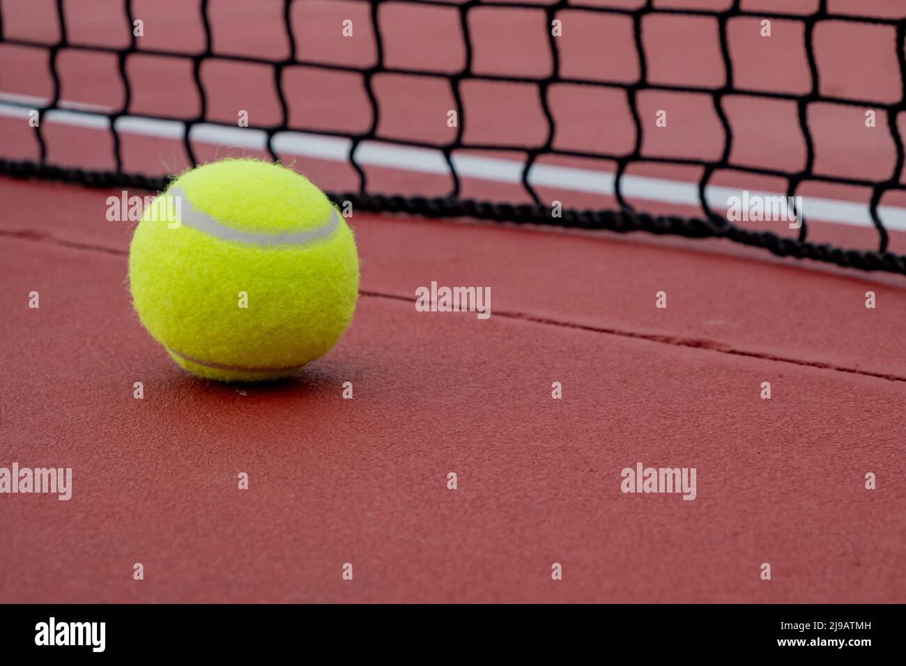 Tennis ball next to the net of a red hard surface tennis court Stock ...