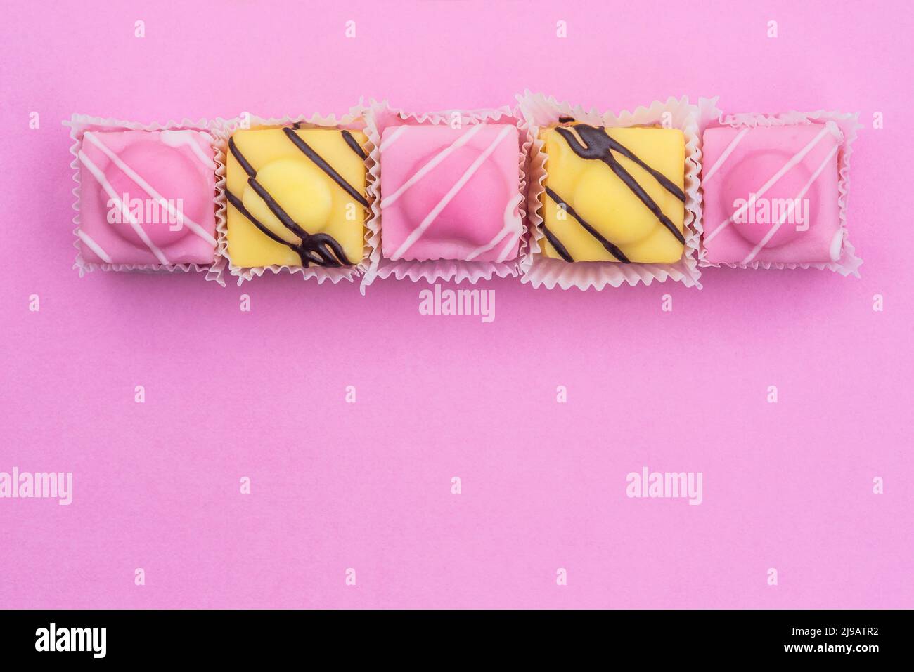 Fondant icing on sponge cakes set on a pastel pink background Stock ...