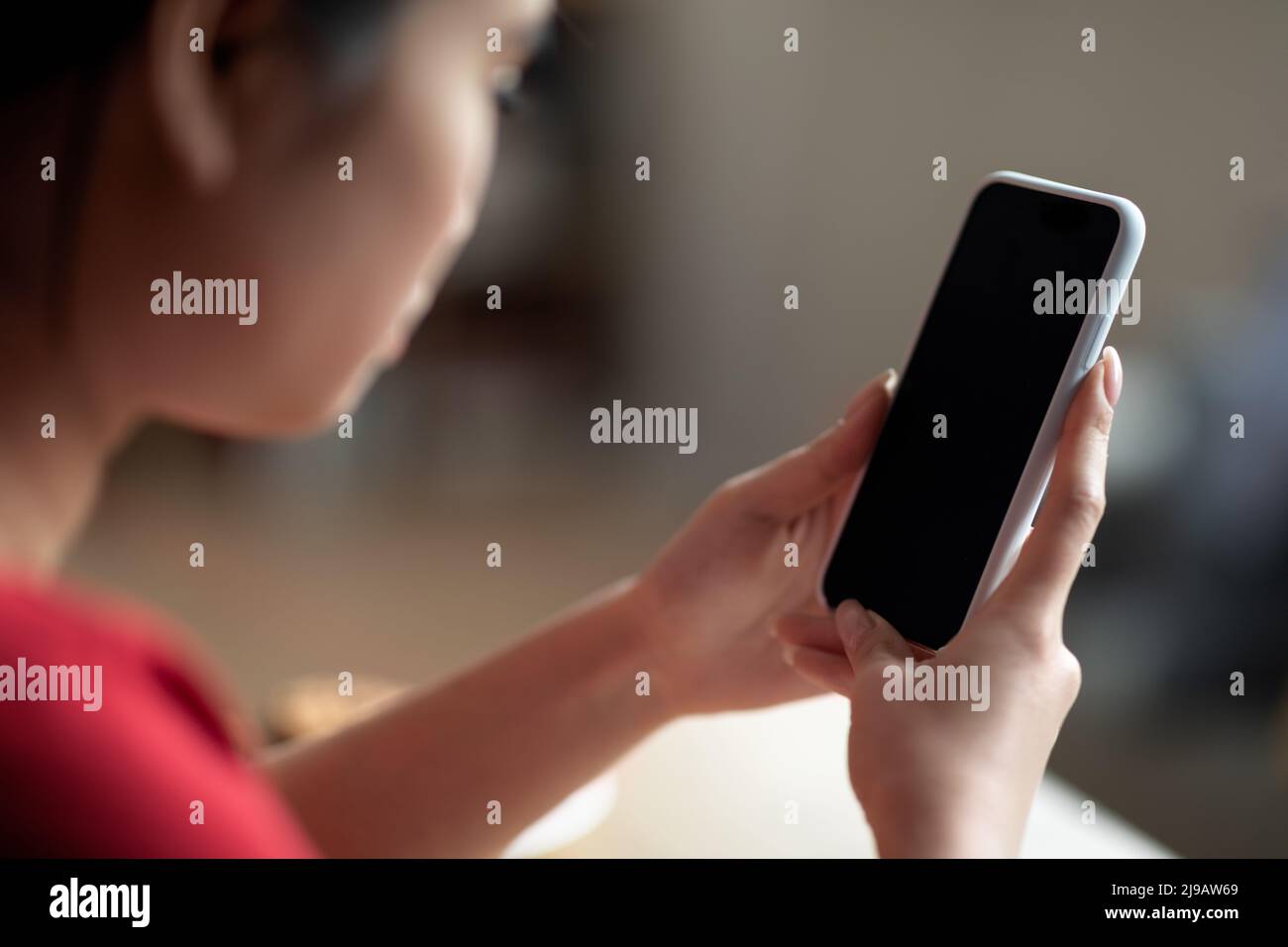 Serious young chinese woman typing on smartphone with blank screen ...