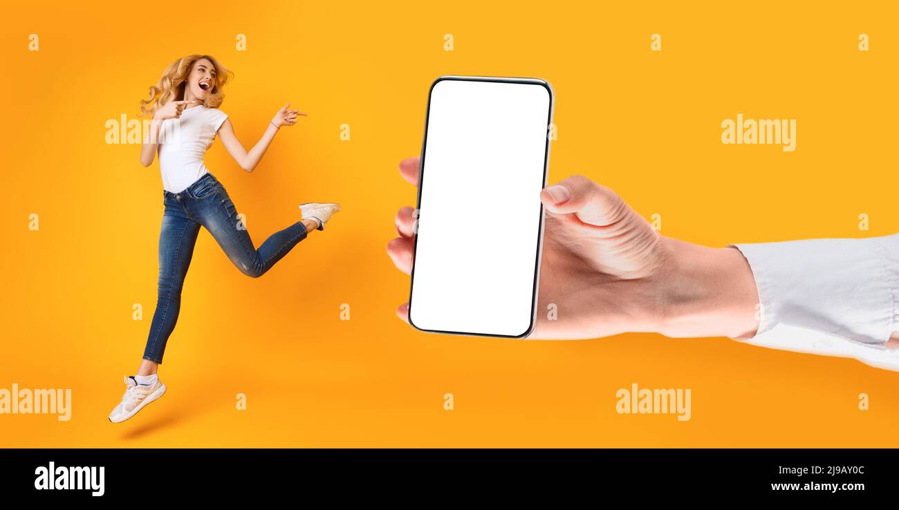 Cheerful lady jumping and pointing at empty smart phone screen Stock ...