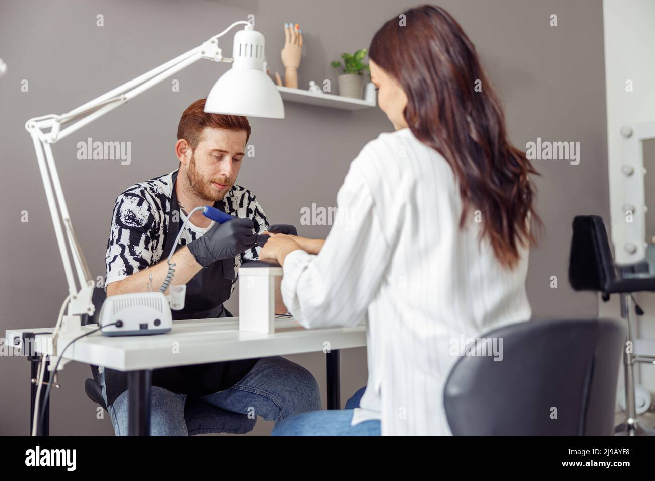 Nail technician doing nail care for client at beauty studio Stock Photo ...
