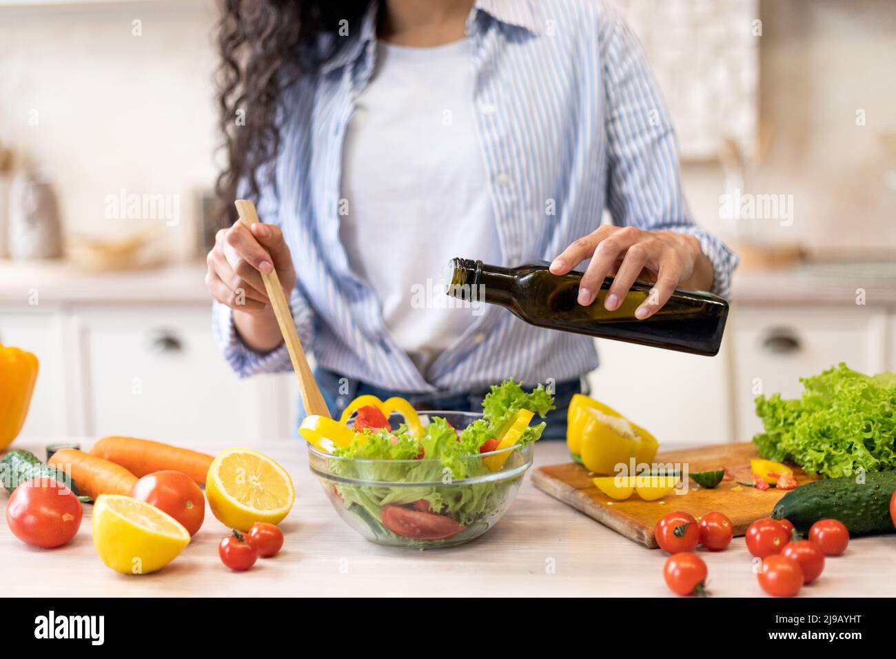 Lady cooking fresh vegetable salad, adding olive oil and seasoning to ...