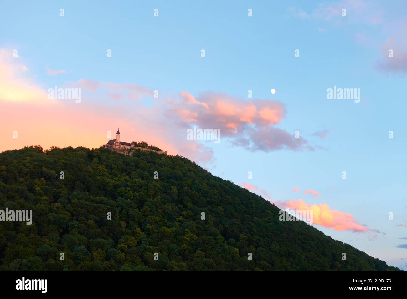 Burg Teck with scaffolding on a large hill, orange clouds and white ...