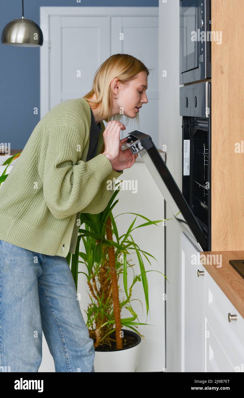 Woman peeks into the oven to check if the food is ready Stock Photo - Alamy