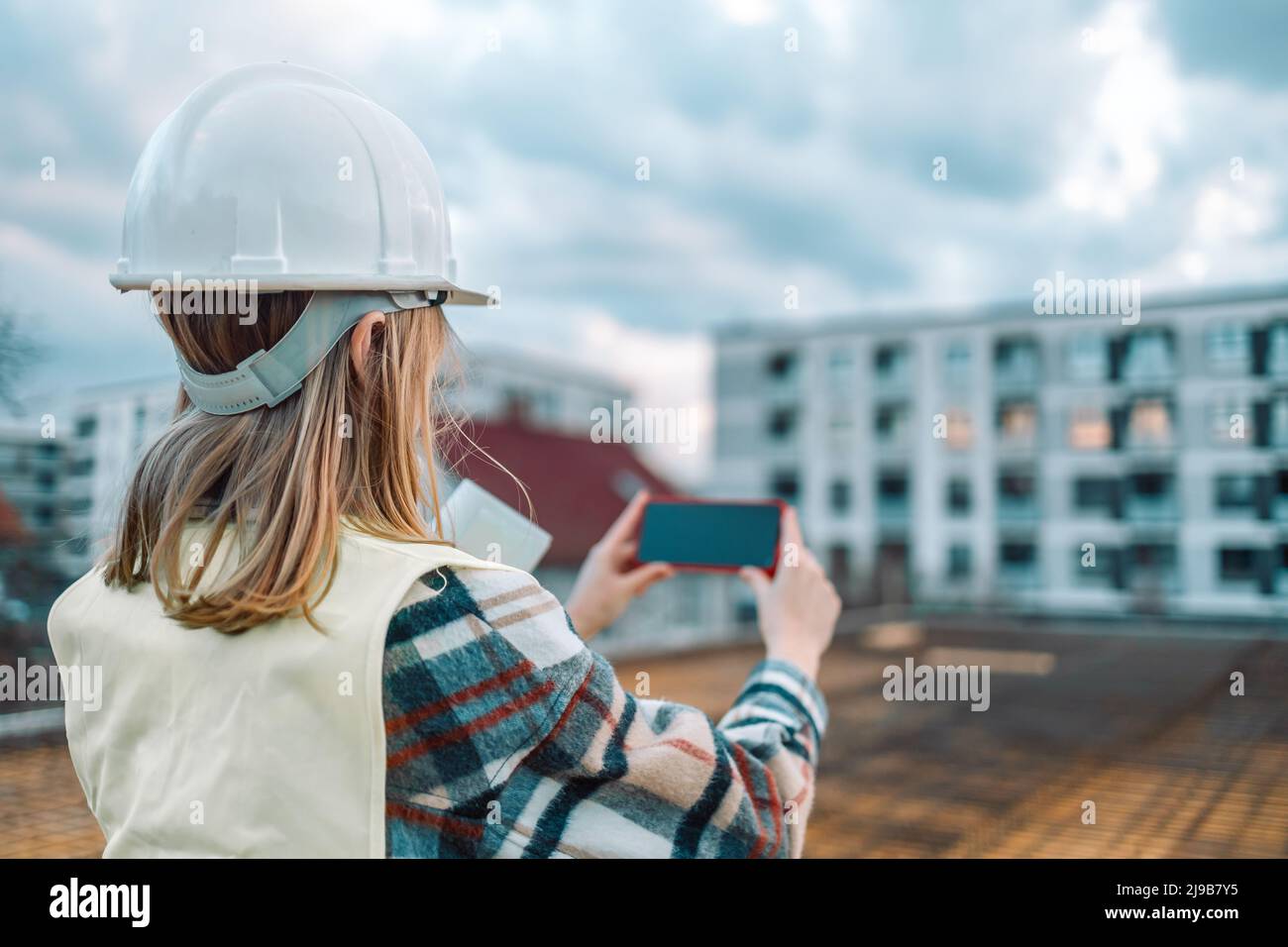 Female architect taking a photo at the construction site checking the ...