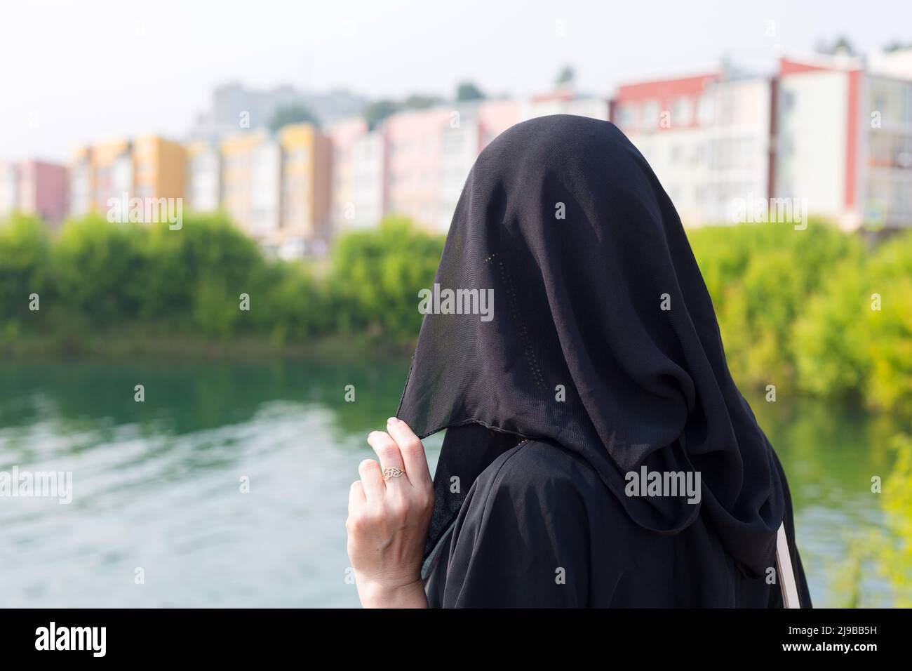 A Muslim woman in a black outfit walks through the city covering her ...