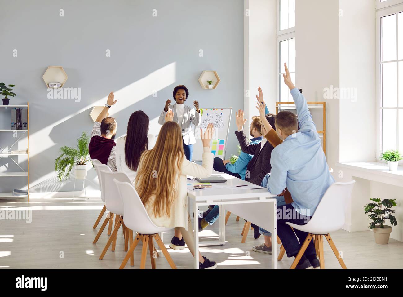 Smiling diverse business people raising hands, successful employees ...