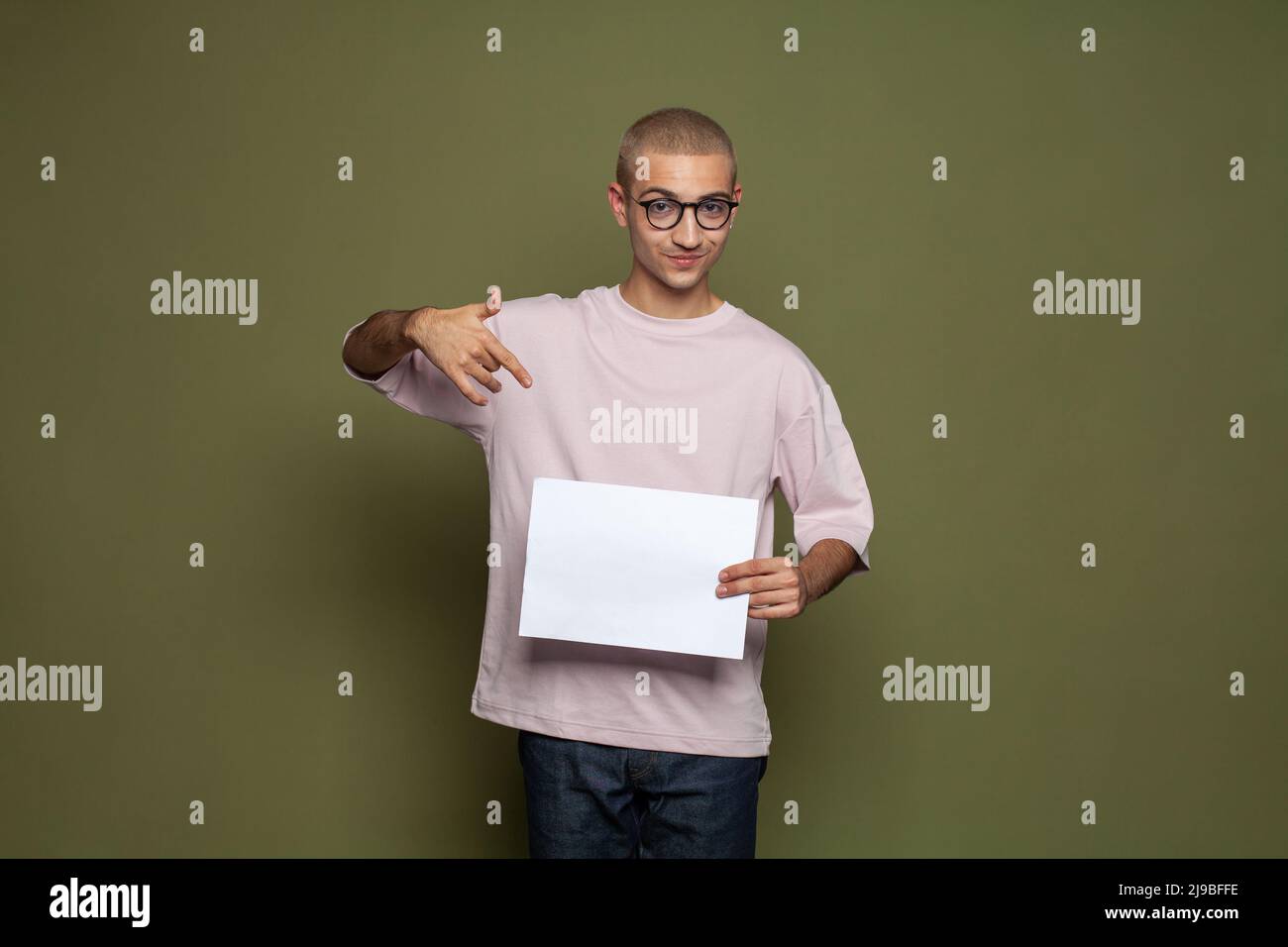 Happy student guy pointing at white empty paper banner on green ...