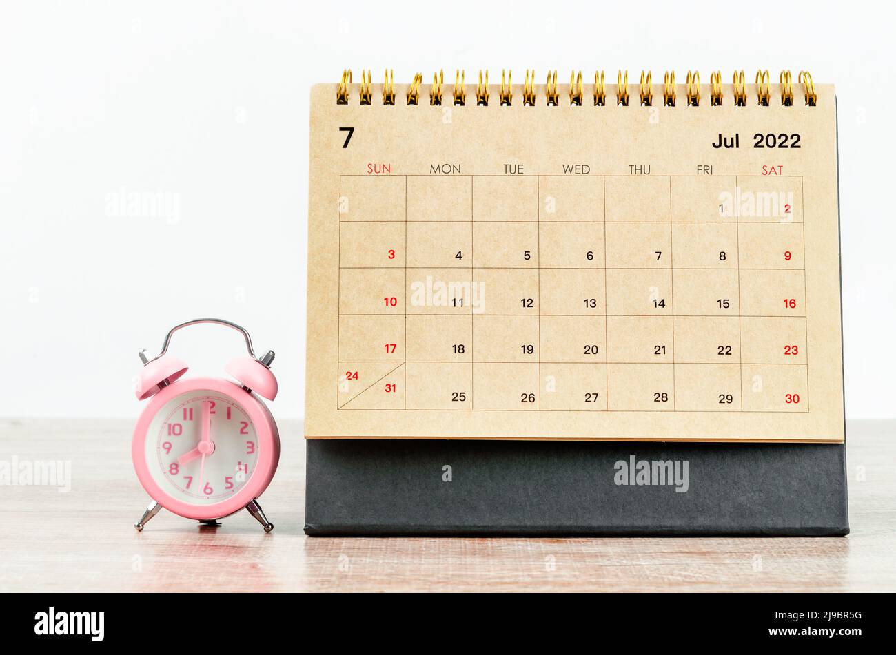The July 2022 Desk calendar with pink alarm clock on wooden table Stock ...