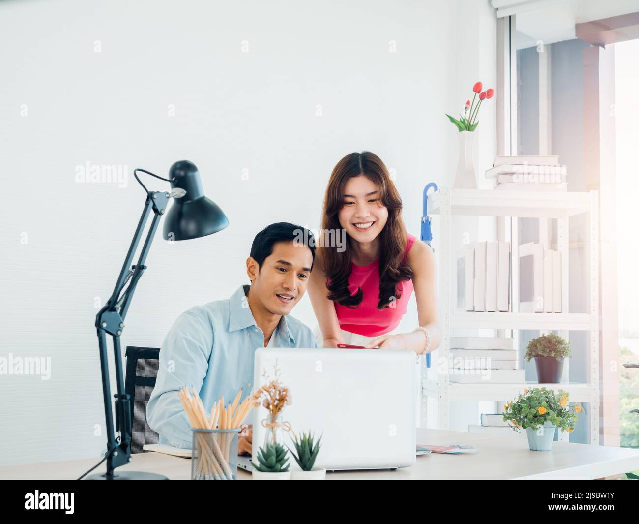 Happy Asian couple, young man and woman using tablet and laptop ...
