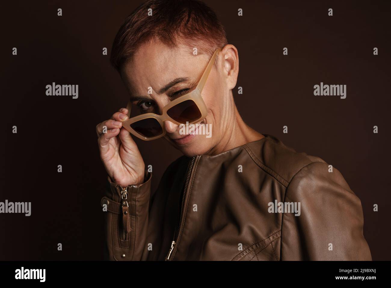 Senior ginger woman in sunglasses winking and smiling at camera ...