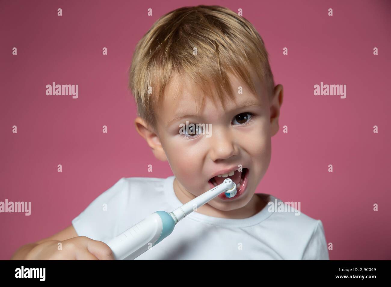 Smiling caucasian little boy cleaning his teeth with electric sonic ...