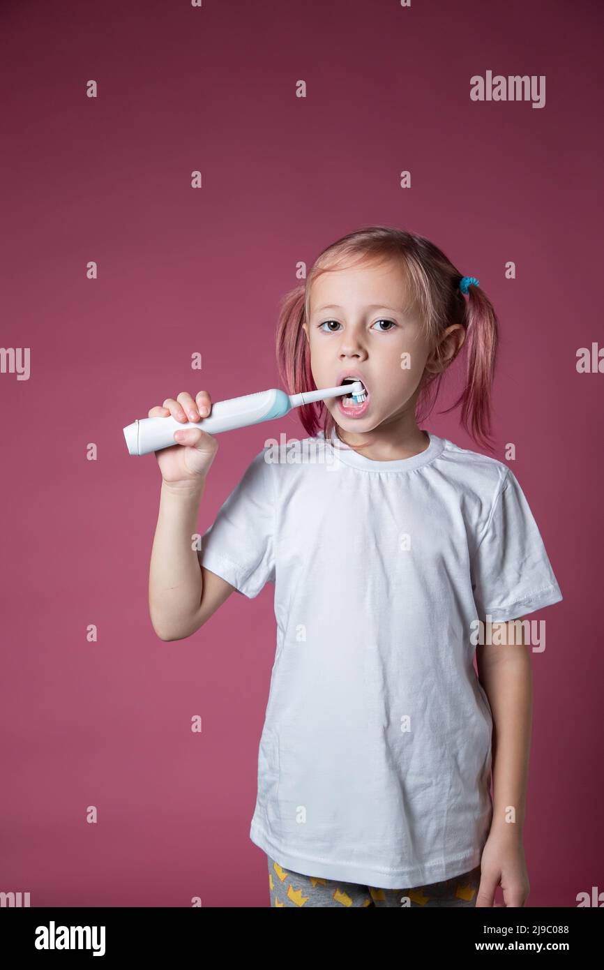 Smiling caucasian little girl cleaning his teeth with electric sonic ...