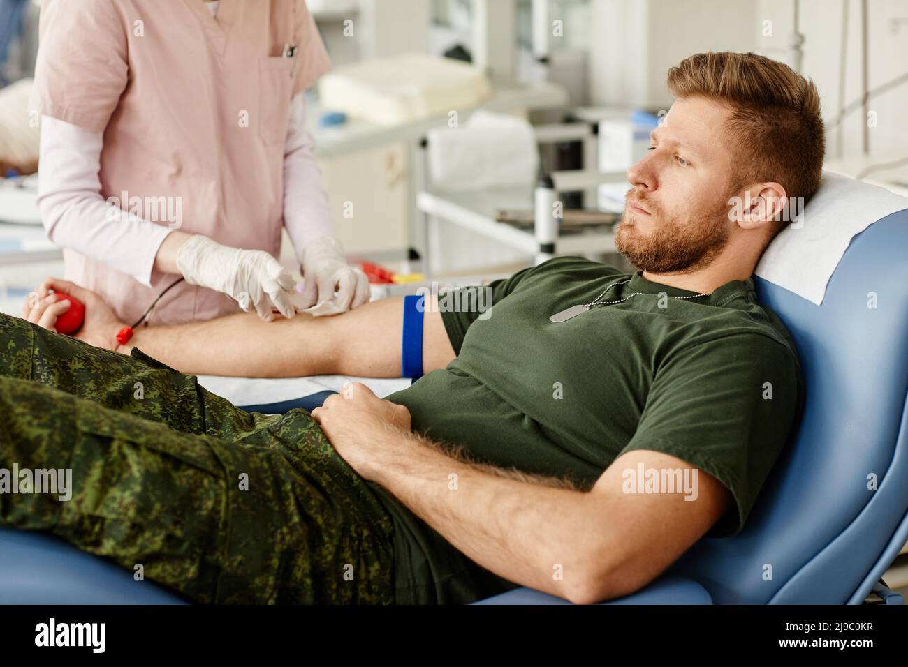 Portrait of male soldier giving blood at donor center with nurse ...