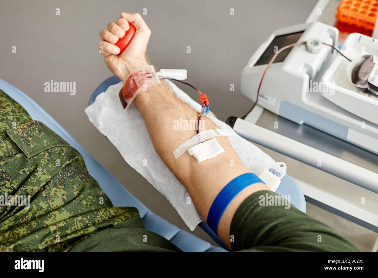 Top view of male donor giving blood and holding red stress ball in hand ...