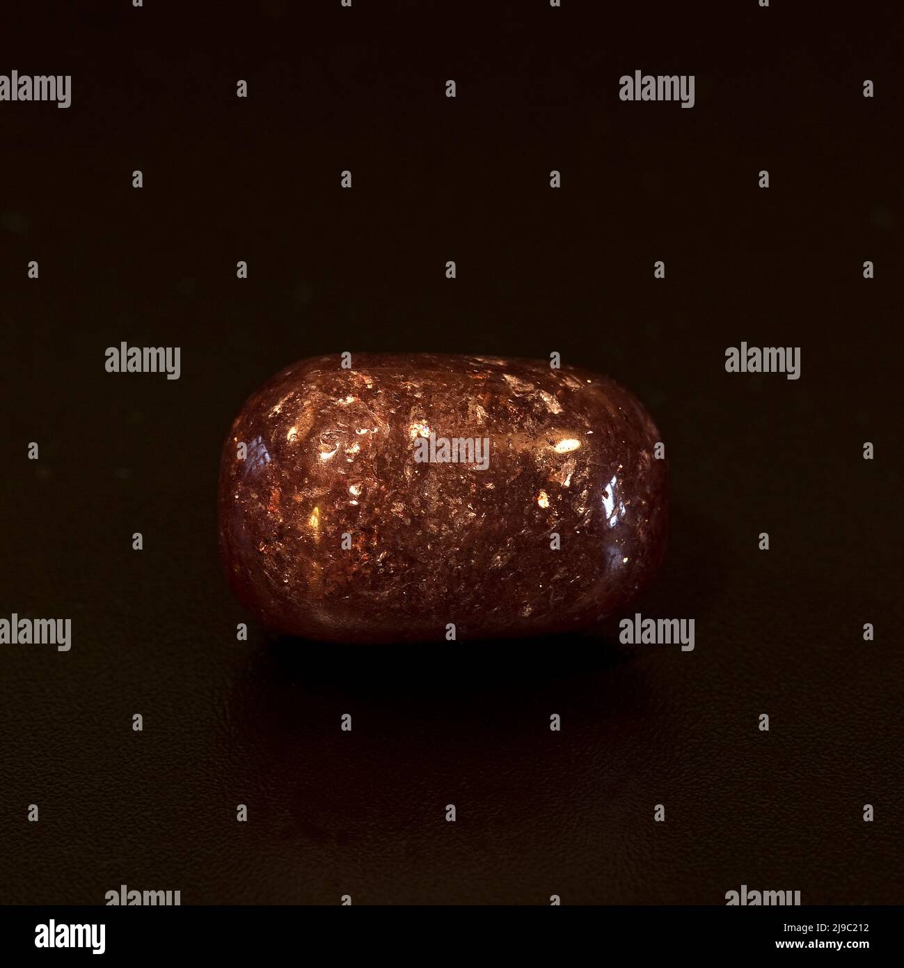 Macro close up colour photograph of a polished 'Red Muscovite' a semi ...