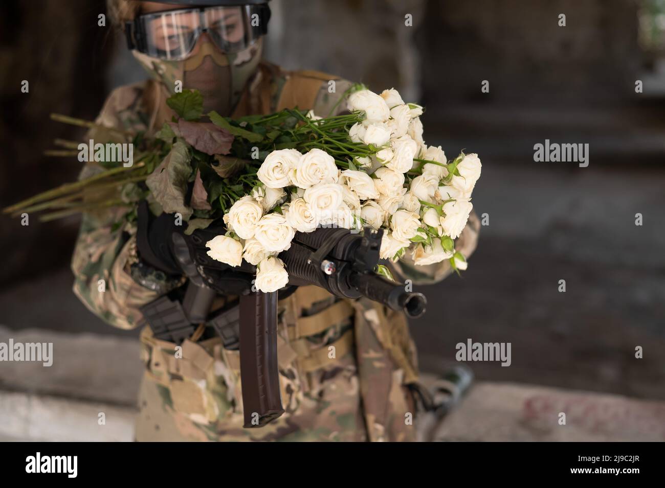Caucasian woman in military uniform holding a machine gun and a bouquet ...