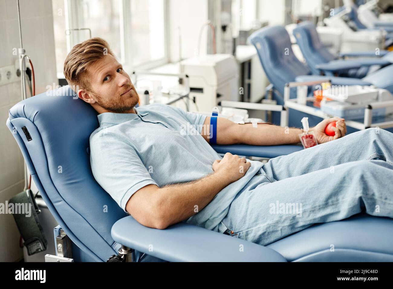 Full length portrait of young man donating blood while lying in ...