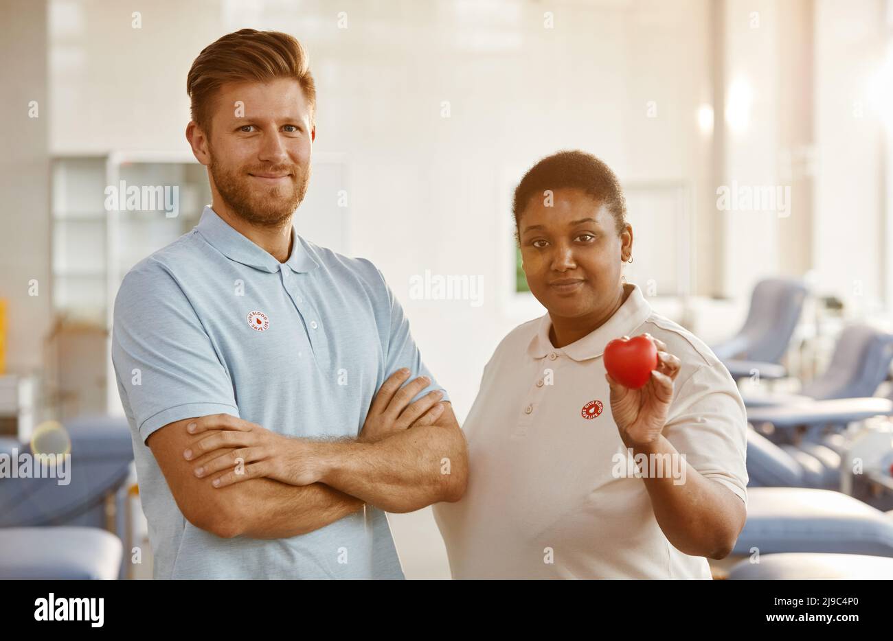 Minimal waist up portrait of smiling blood donors holding red heart to ...