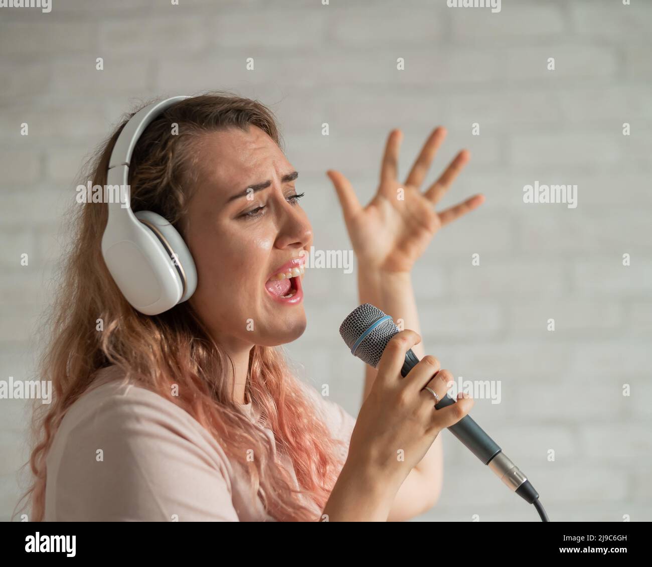 Close-up portrait of a caucasian woman with curly hair singing into a ...